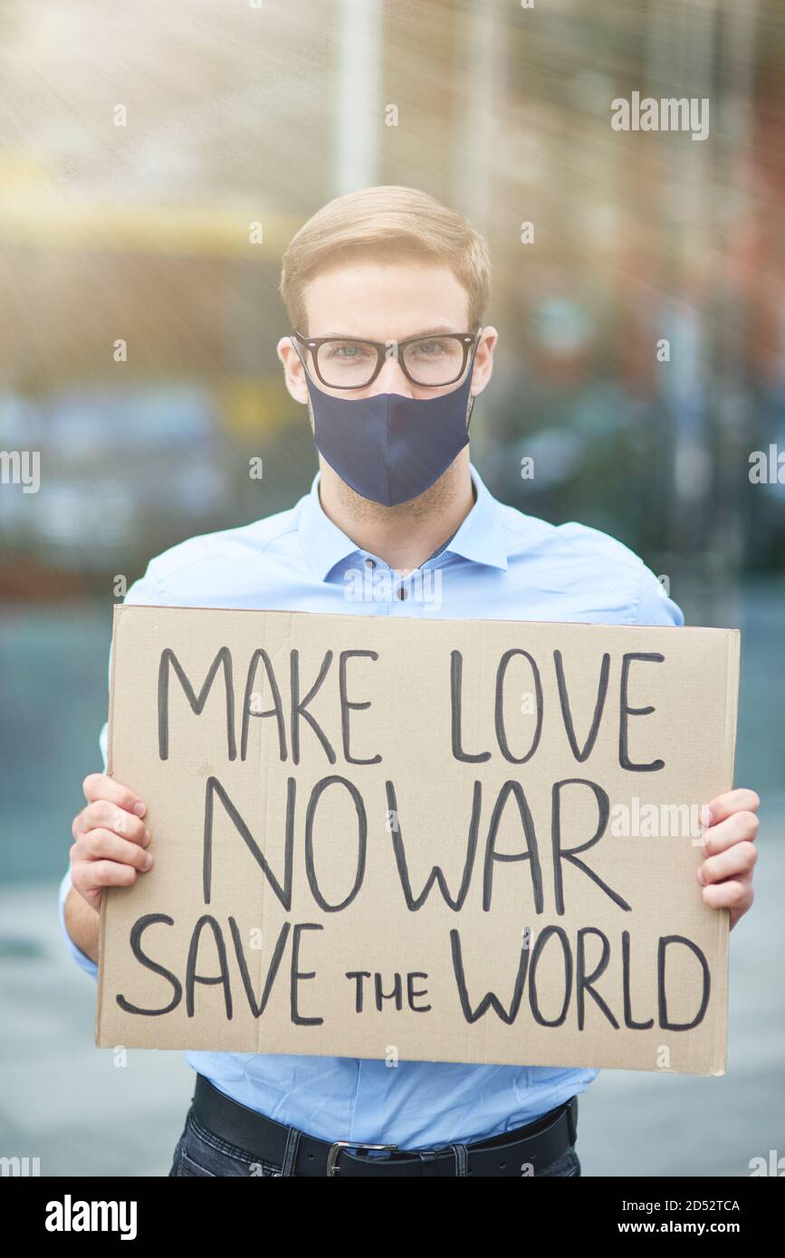 Vertical of young male activist wearing black protective mask holding ...