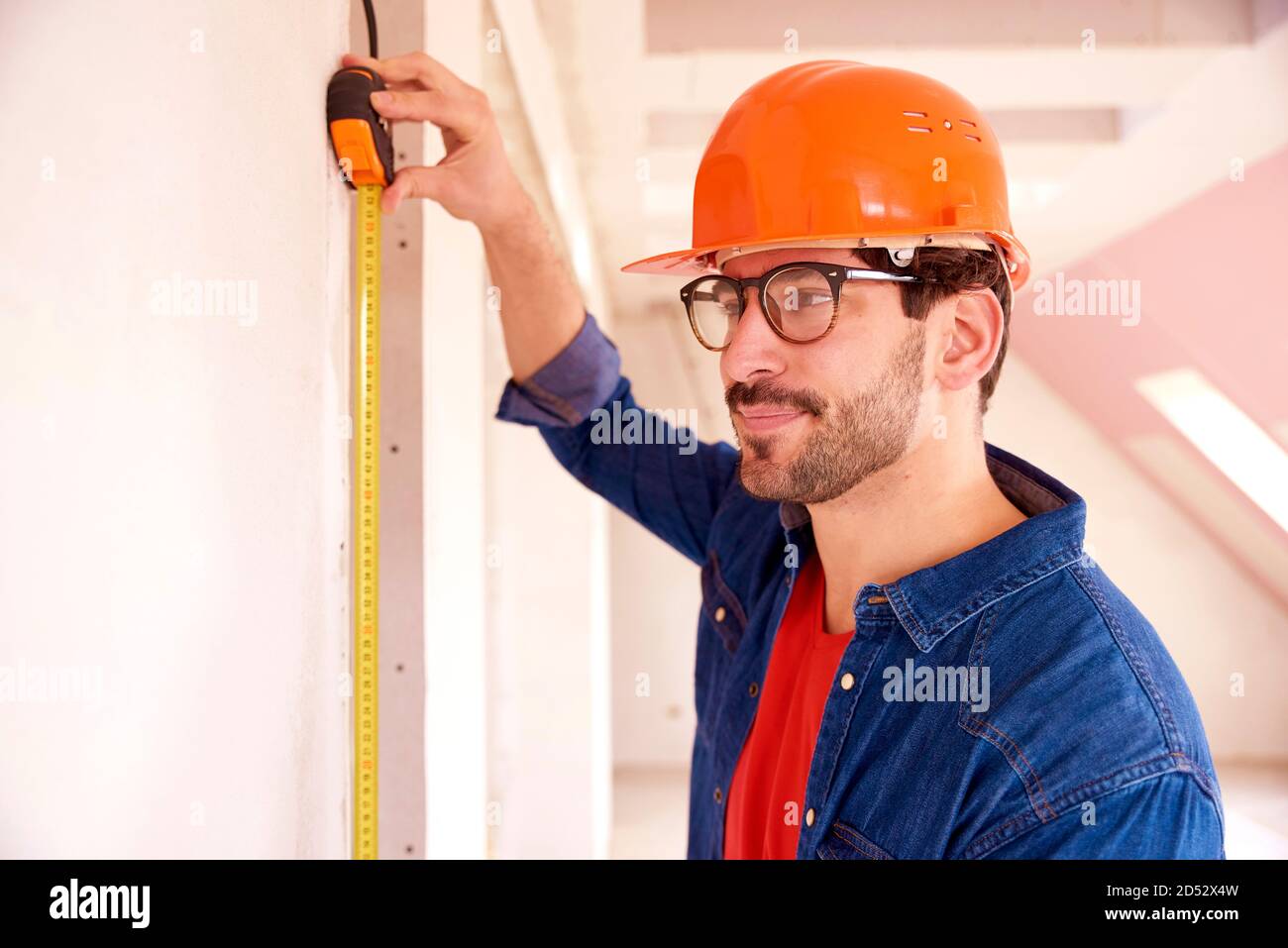 Portrait of young man using measuring tape while working on ...