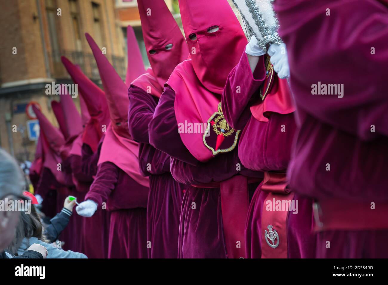 Procession of Catholic devotees in maroon capirotes during the Holy ...