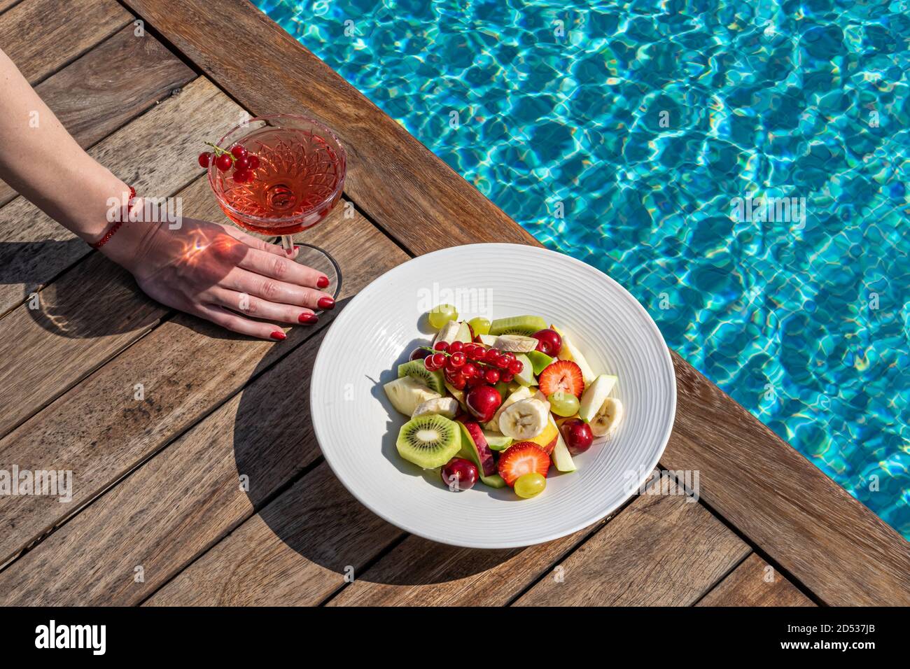 refreshing cocktail and fruits and berries plate near swimming pool in ...
