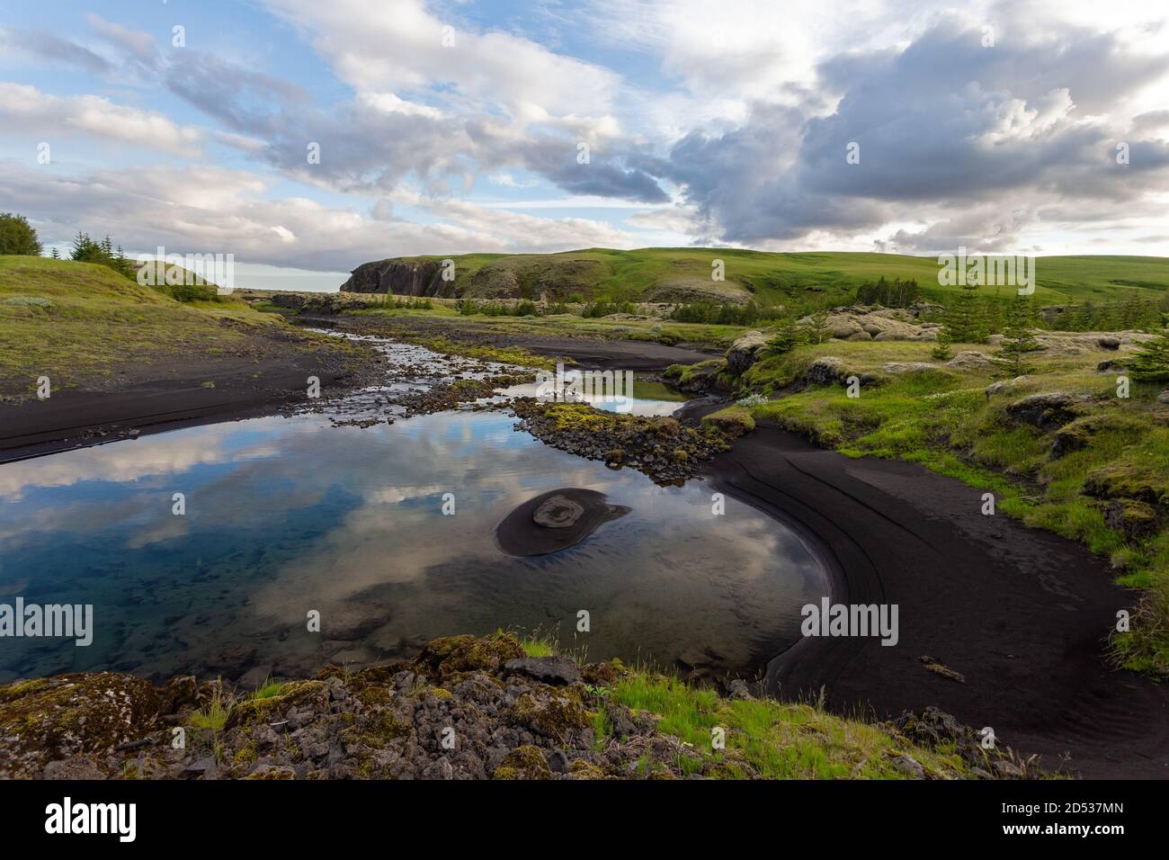Summer nature scenery with black sand on a riverbank and clouds in the ...