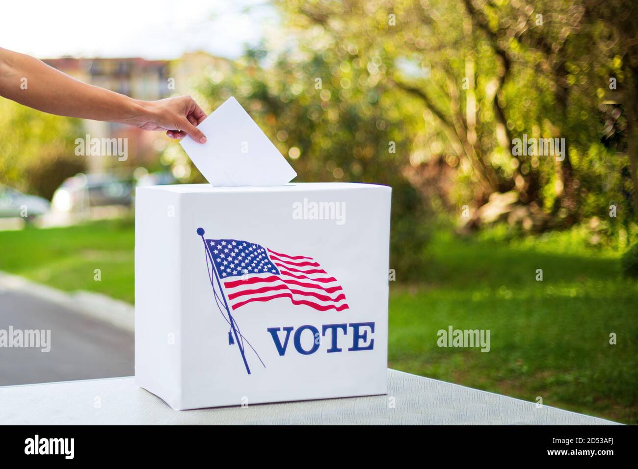Hand putting vote into ballot box on table outside Stock Photo - Alamy