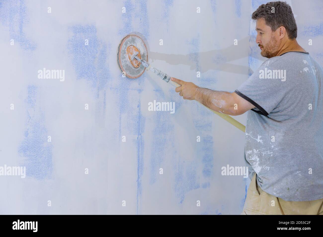 Worker smoothing and finishing wall with sanding the plaster ...