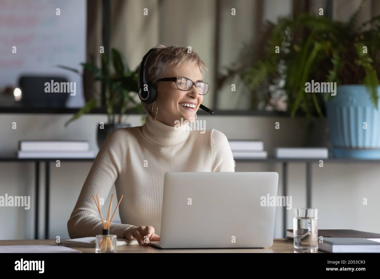 Smiling female employee in headphones laugh talking on video call Stock ...