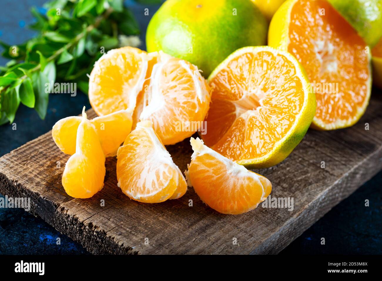 Ripe Mandarin fruit peeled open and place on old rustic look timber ...