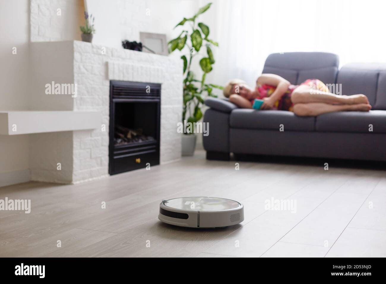Cleaning concept - automatic robotic hoover clean the room while woman ...