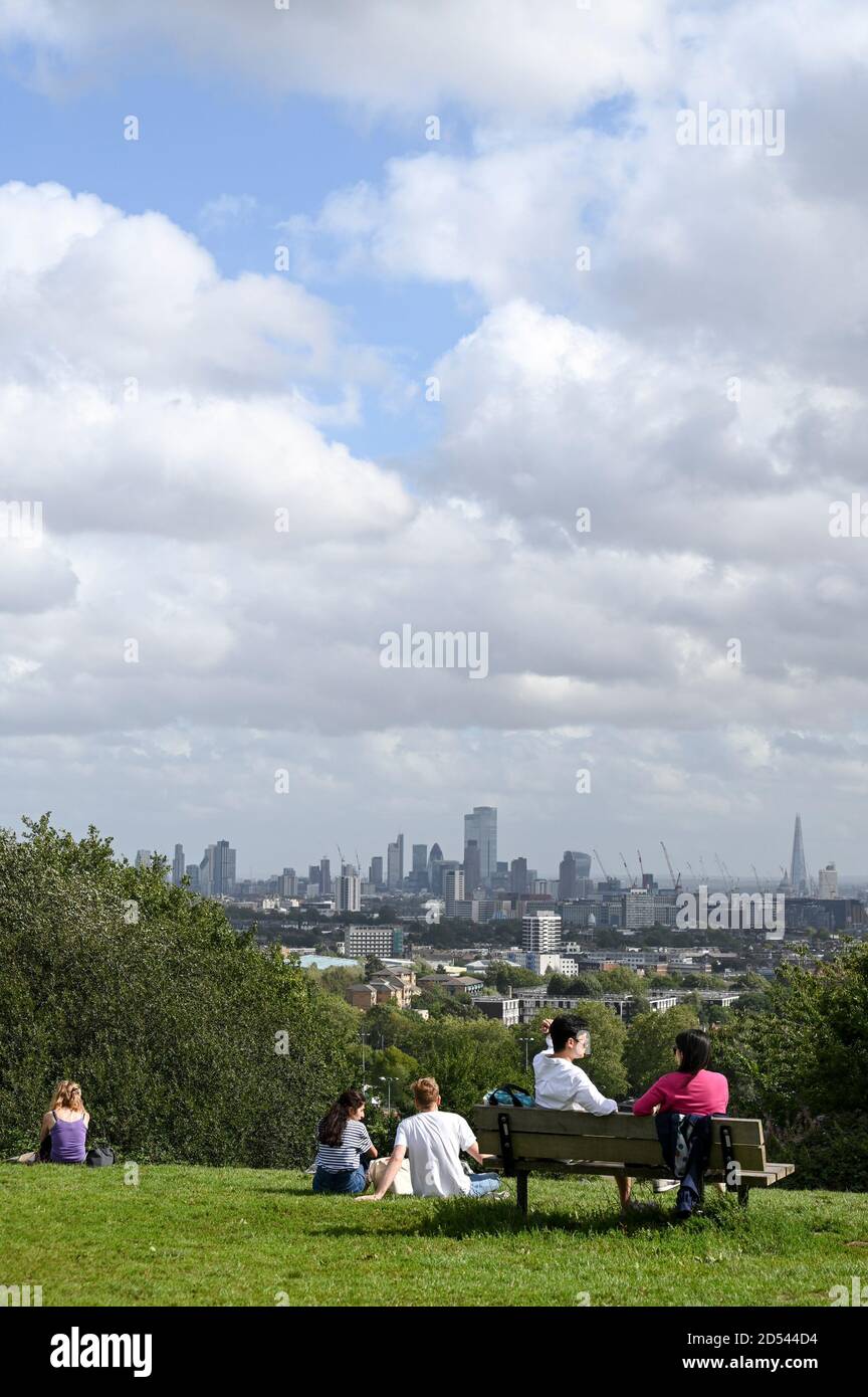 People chatting in small groups on Parliament Hill, London UK, with a ...