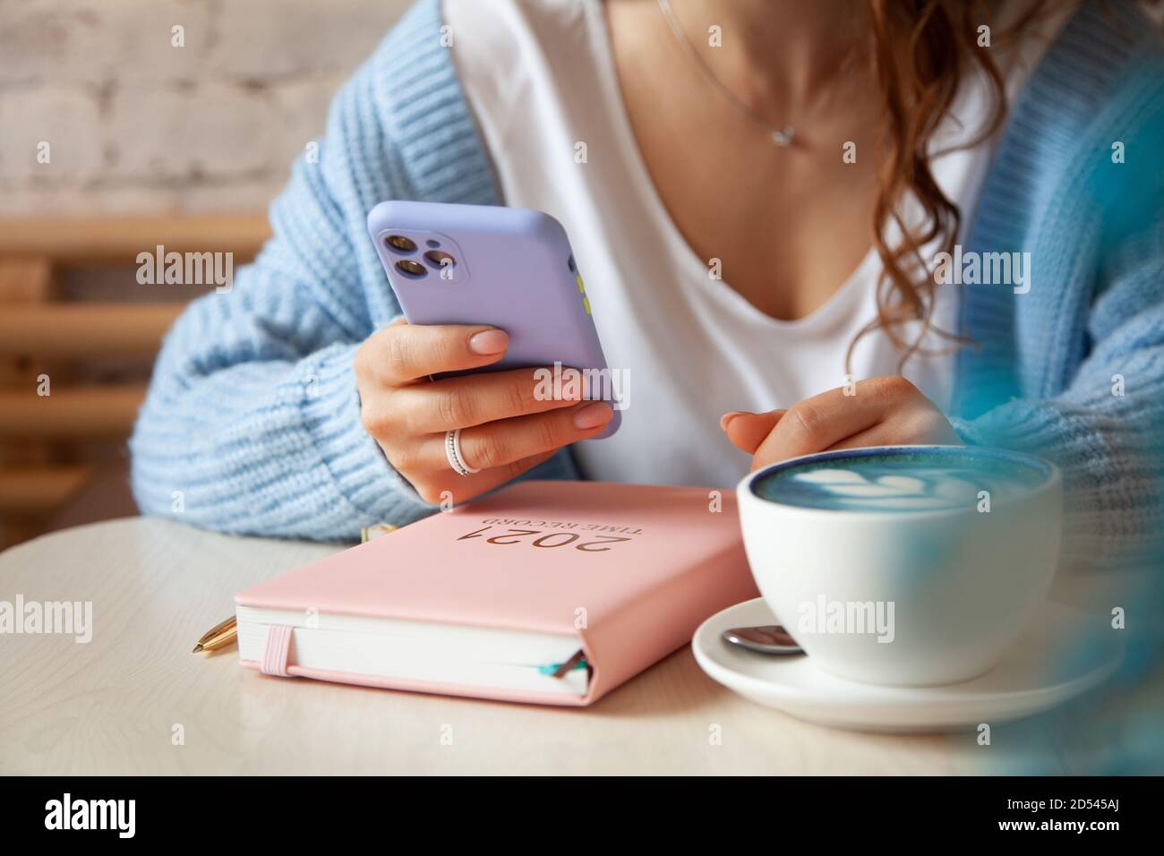 Young woman in blue warm sweater is reading a text message from mobile ...
