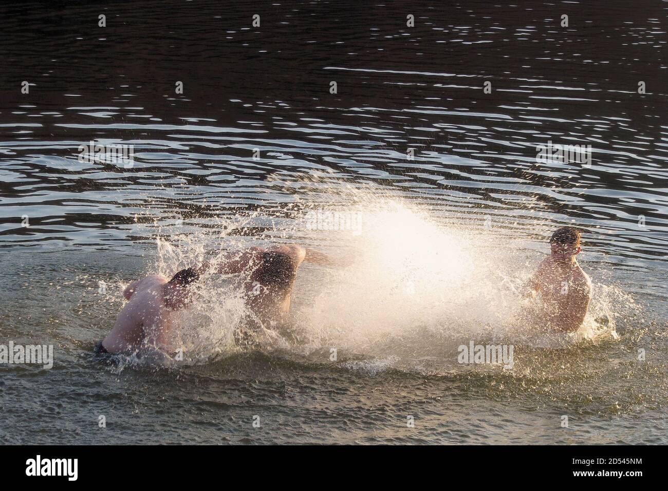 Adults splash each other in the water. Men play in the water ...