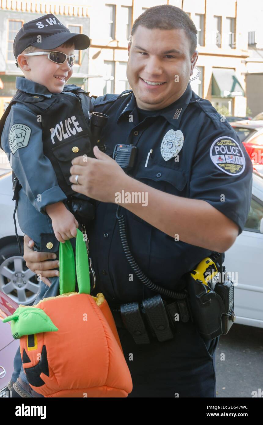 A policeman holds his son, who is dressed as a policeman for Halloween ...