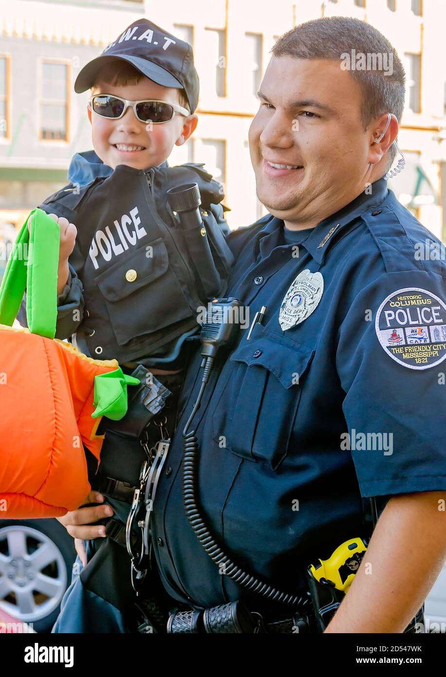 A policeman holds his son, who is dressed as a policeman for Halloween ...