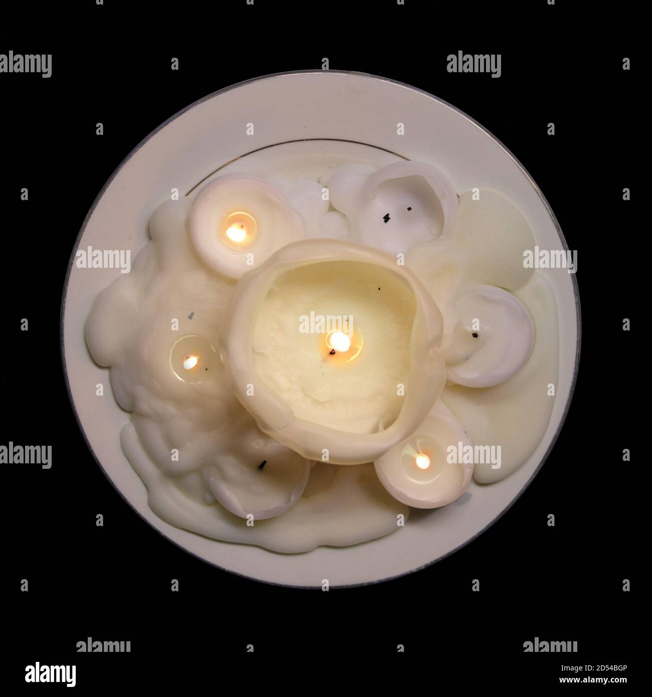 Top view of a melted candle cluster on a plate with flames Stock Photo ...