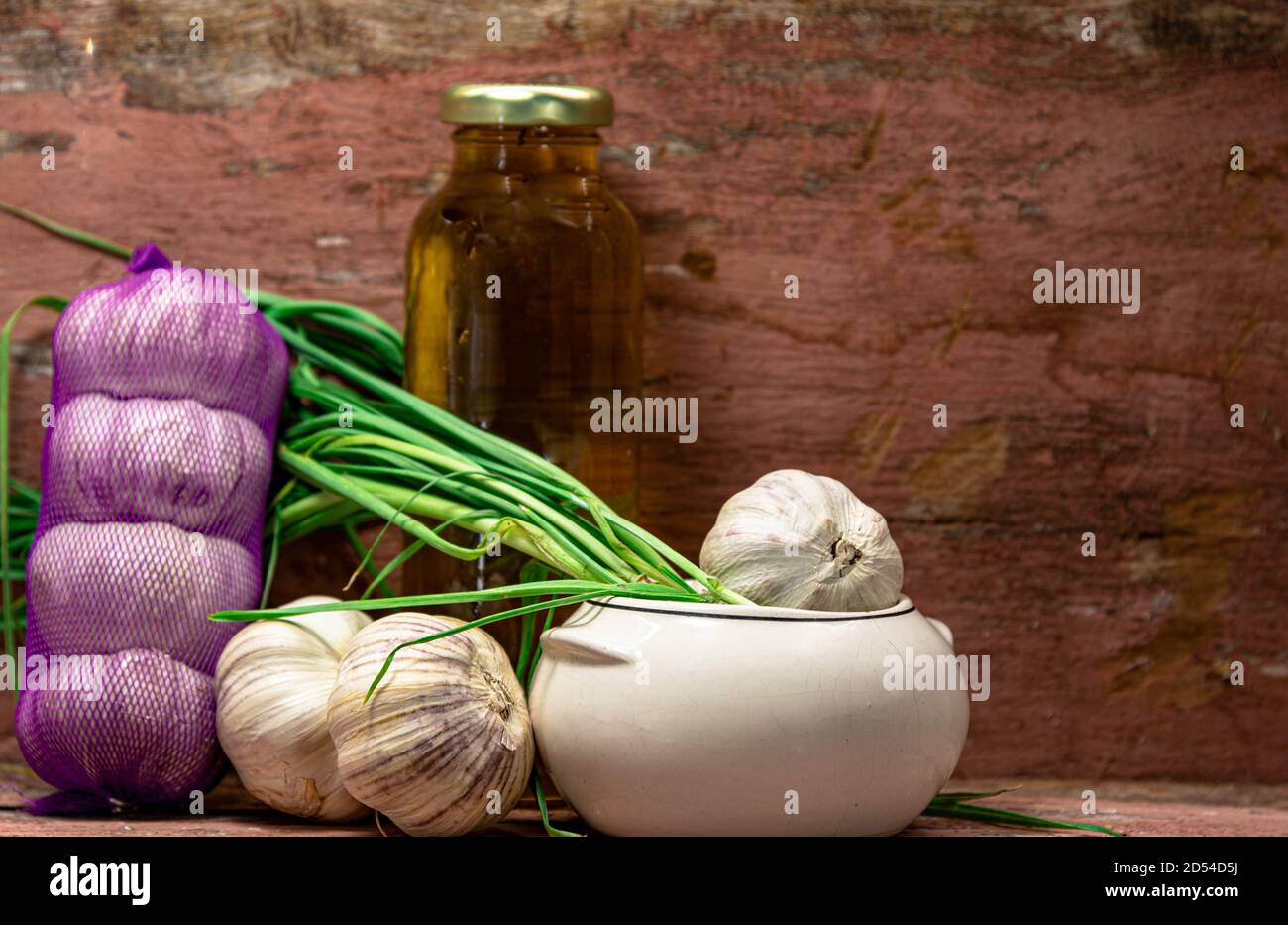 Glass of olive oil. Bulbs of processed and fresh garlic. Green leaves ...