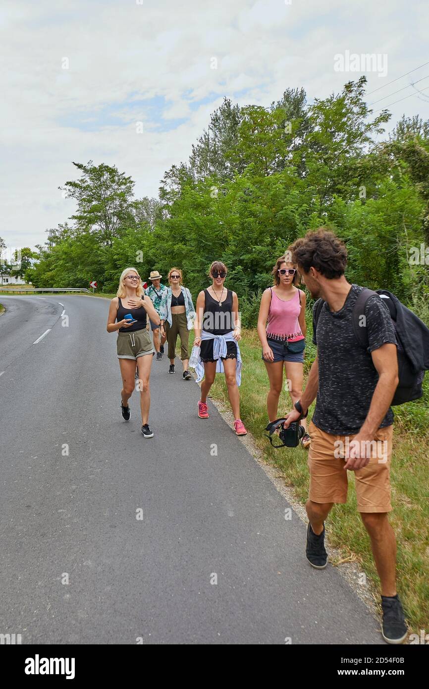 Young group of friends walking by the road Stock Photo - Alamy