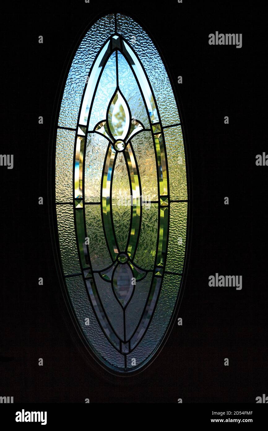 Stained glass window with iron detail and a blue sky with green grass ...