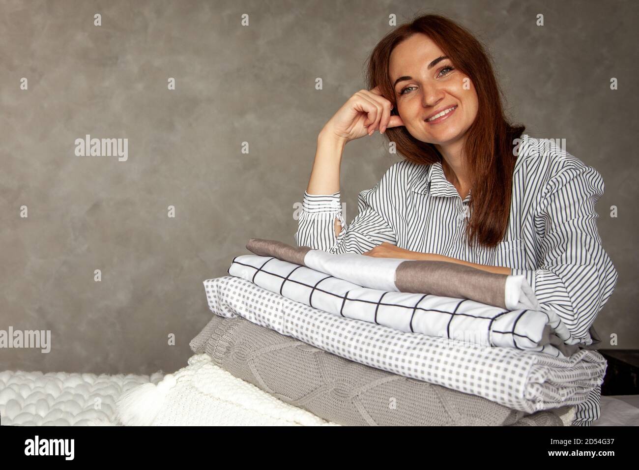 Beautiful woman in winter thick warm robe is sitting and neatly folding ...