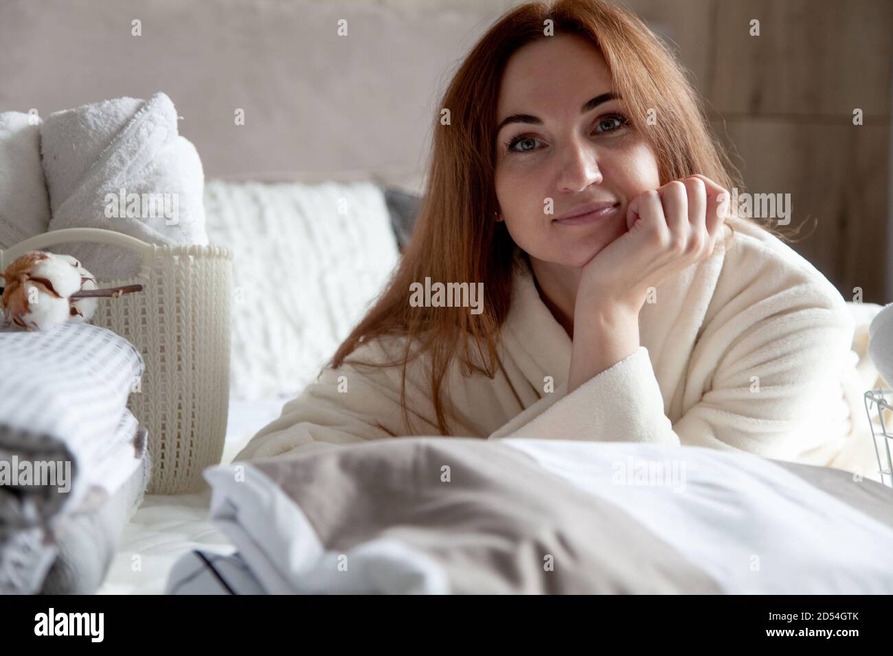 Beautiful woman in winter thick warm robe is sitting and neatly folding ...