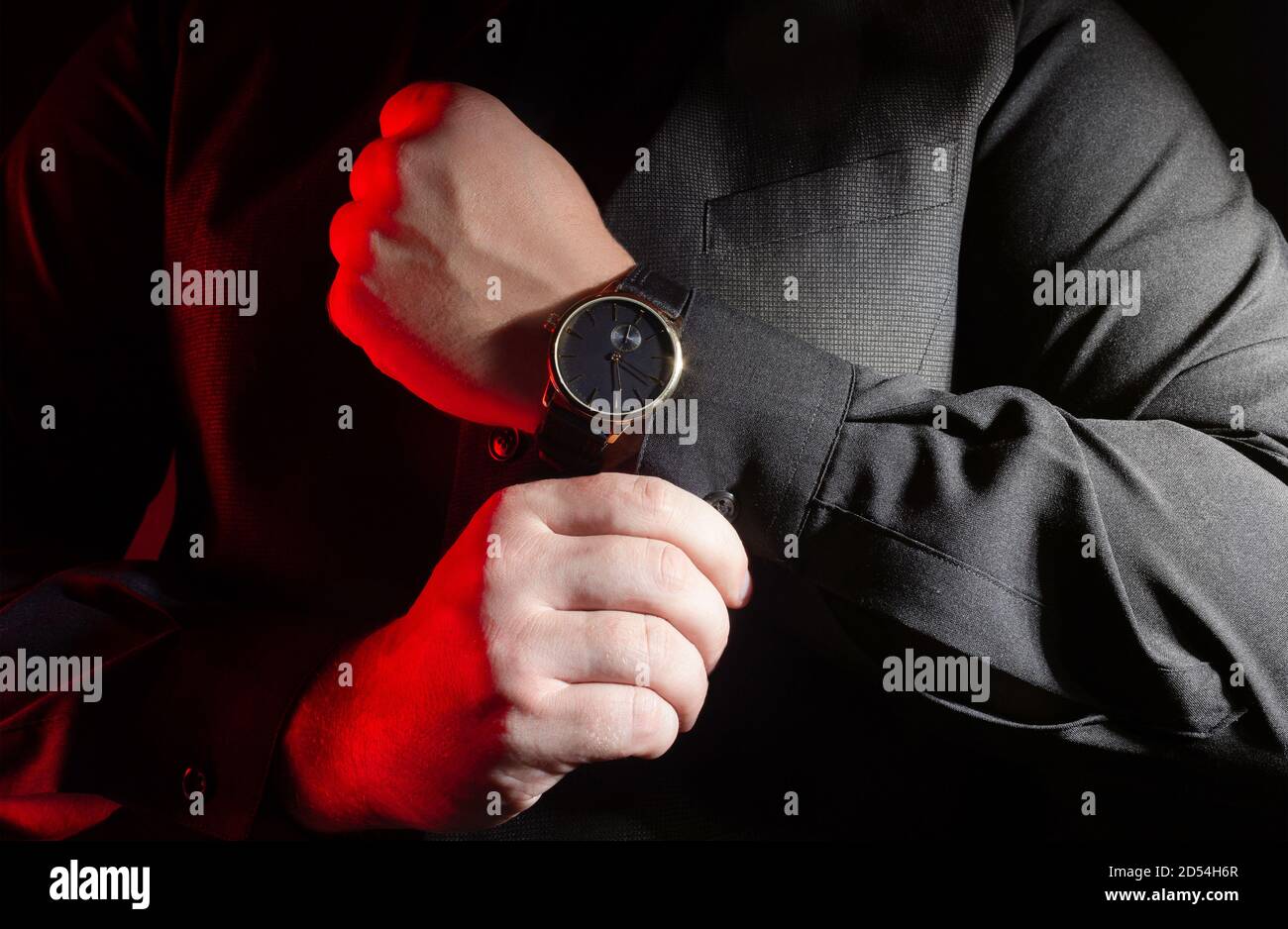 Photo of a male arms in black shirt and vest putting on elegant watch ...