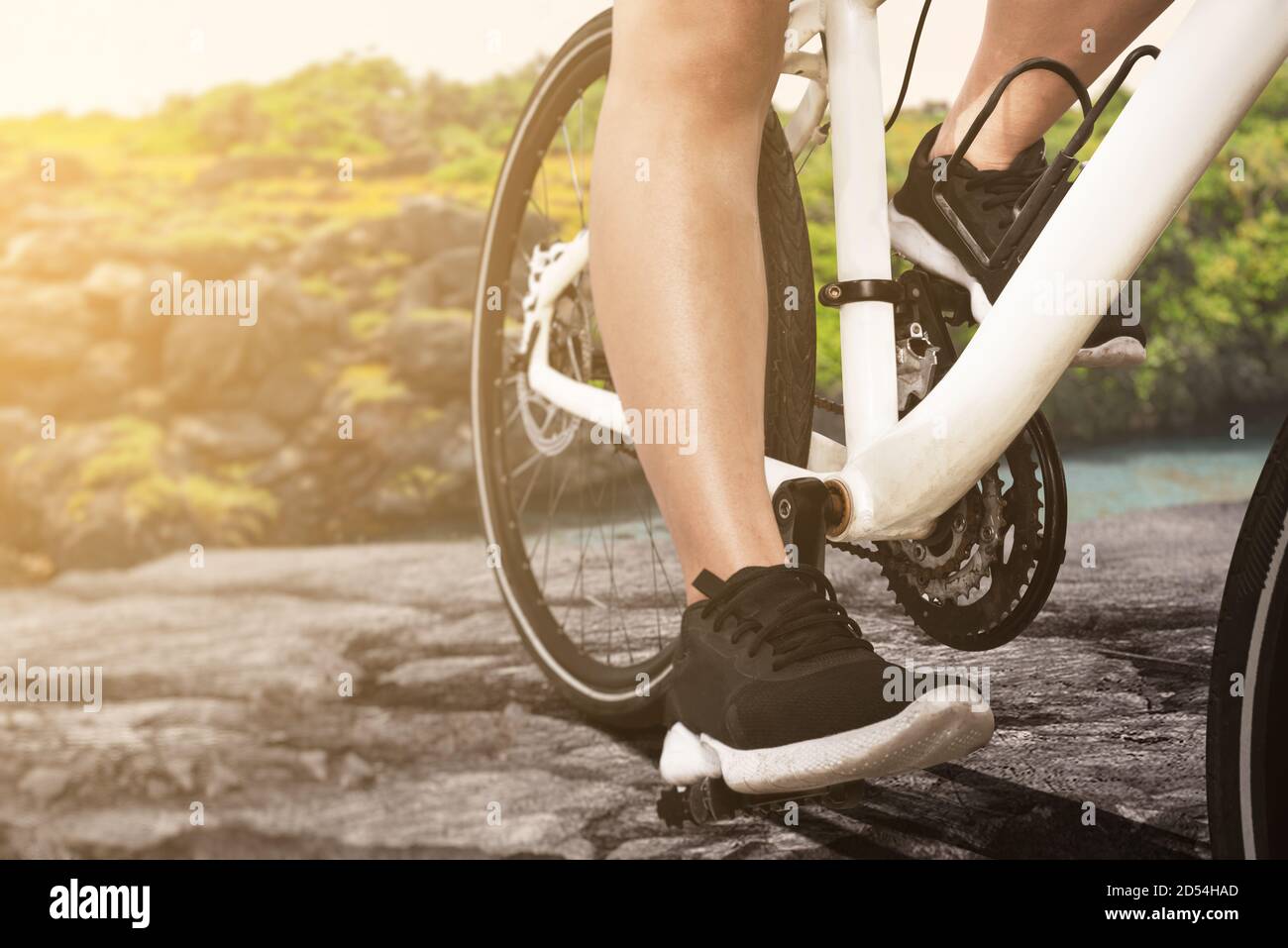 Side view of a woman riding a bicycle on the cliff with the sunlight ...