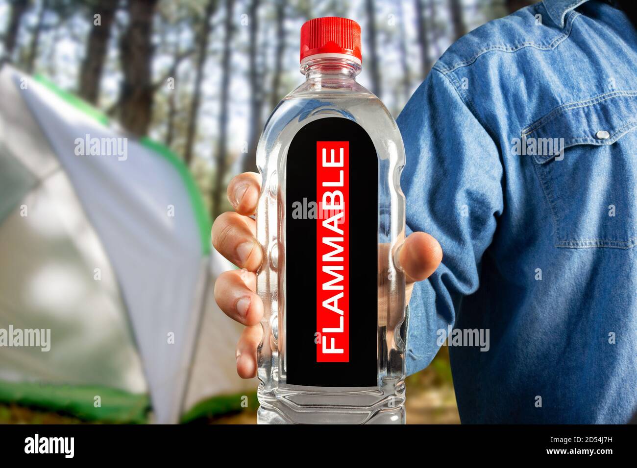 Photo of male hand in shirt holding flammable liquid bottle on forest ...