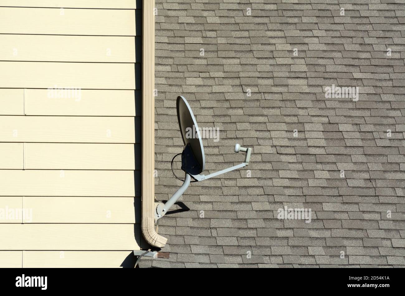 Satellite disc antenna on side of building with roof shingles and ...