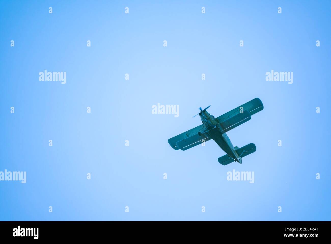 Retro green biplane plane in the blue sky. Old airplane against blue ...
