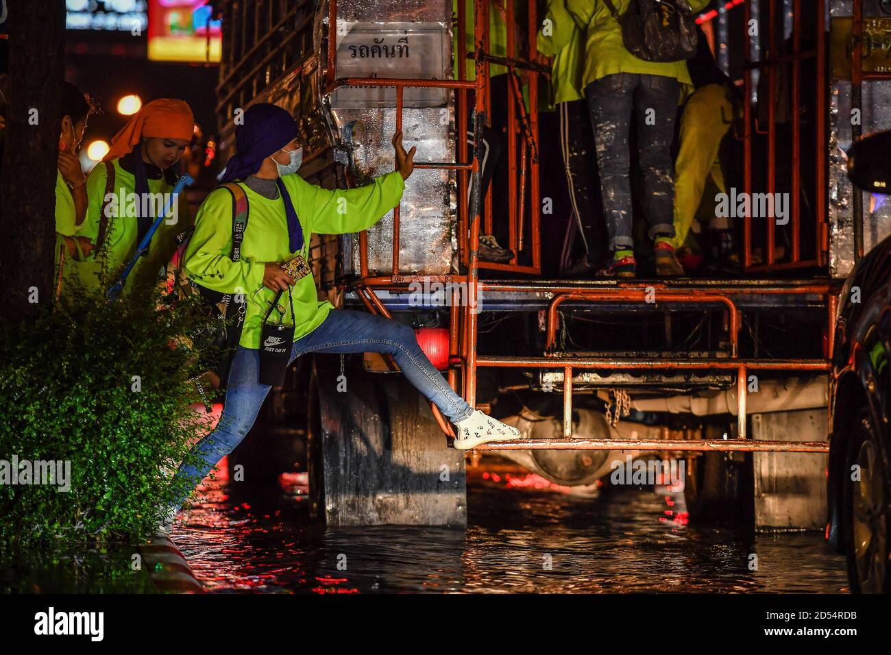 Construction workers Try to step on the bus through a flooded street ...