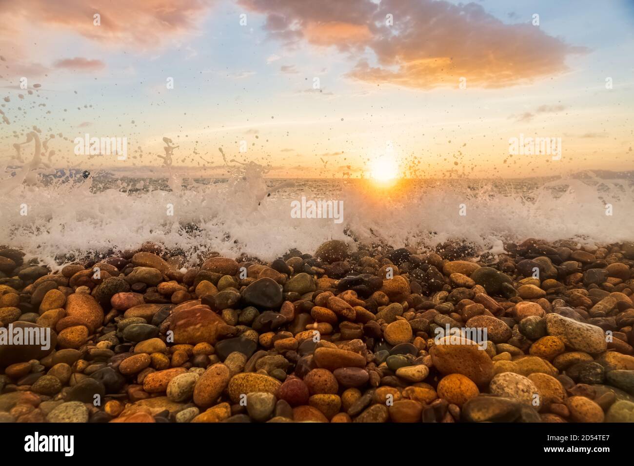 A Sunset Ocean Wave is Breaking on the Sea Shore with the Sun Setting ...