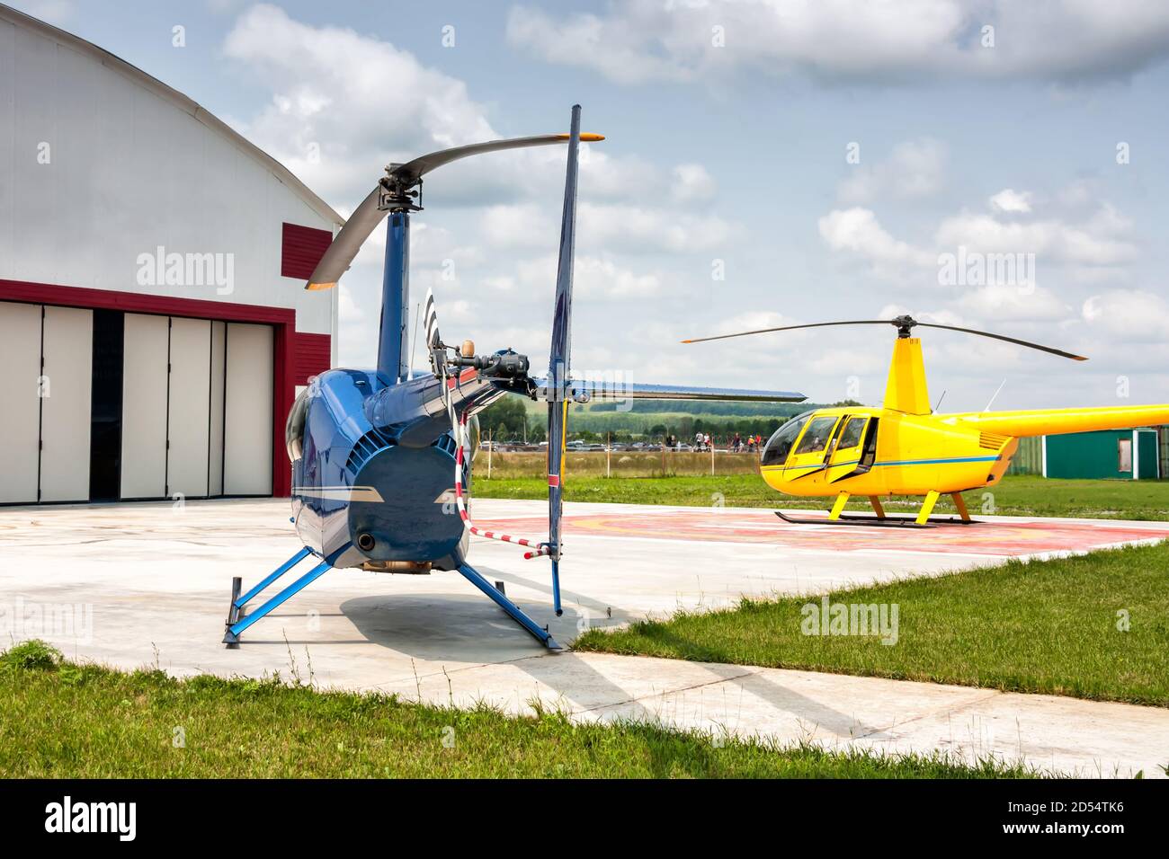 Helipad with two small helicopters beside the hangars Stock Photo - Alamy