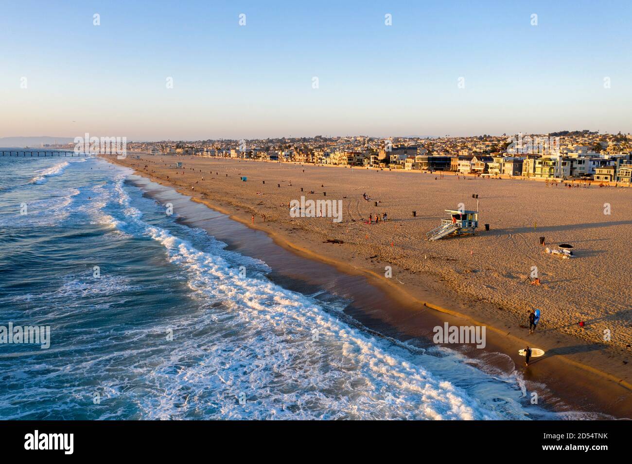 Aerial view of surfers coming in from the ocean at sunset in Hermosa ...