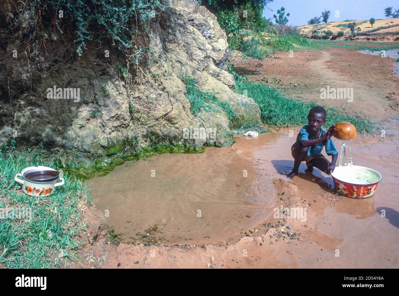 Niger. Village Boy Gathering Water from a Natural Spring Stock Photo ...