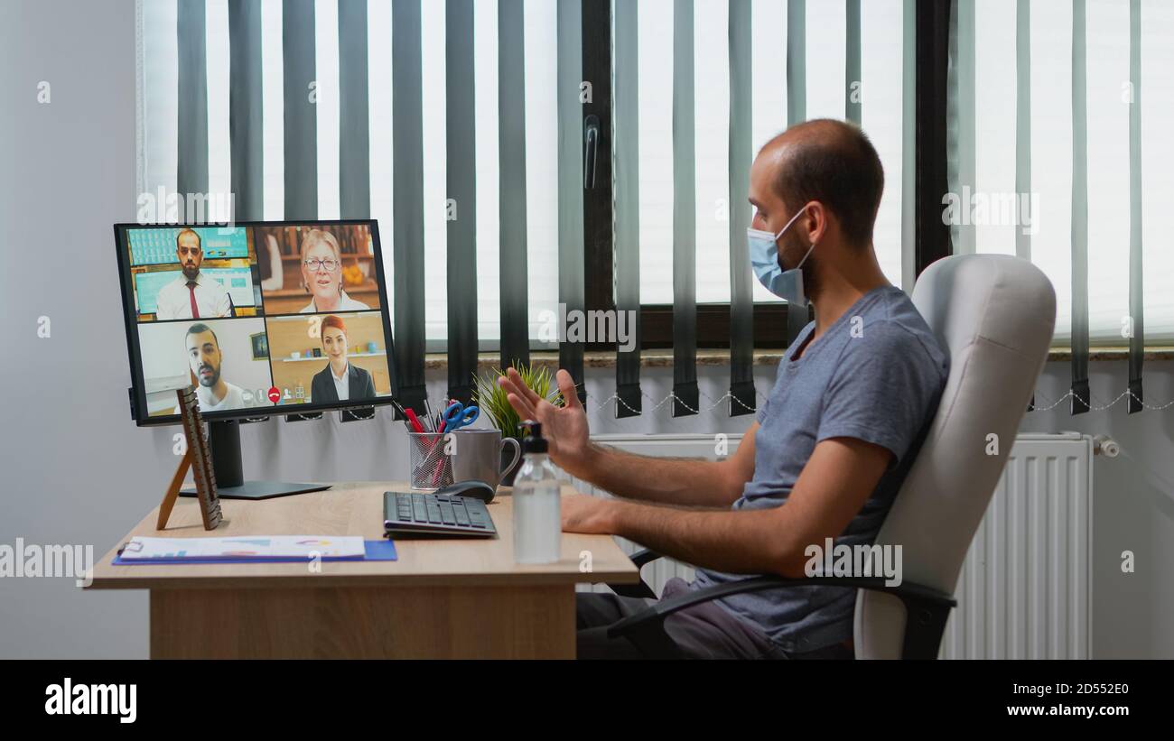 Freelancer making a video conference with face mask in modern office ...