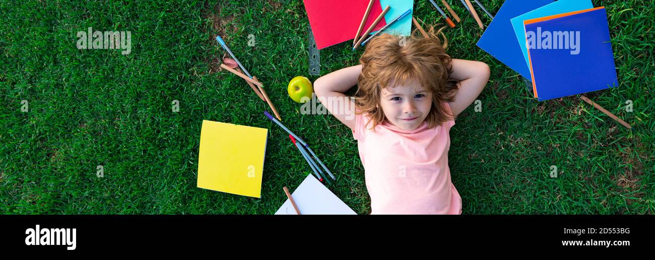 Portrait of cute smart clever school boy nerd doing homework, lie on ...