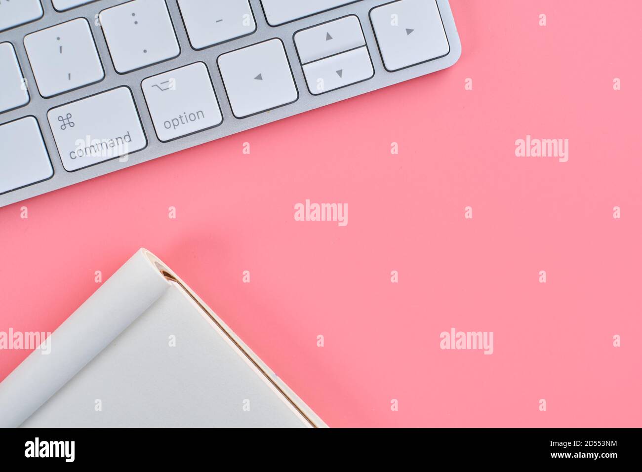 Top view of a notepad and a keyboard on a pink background with copy ...