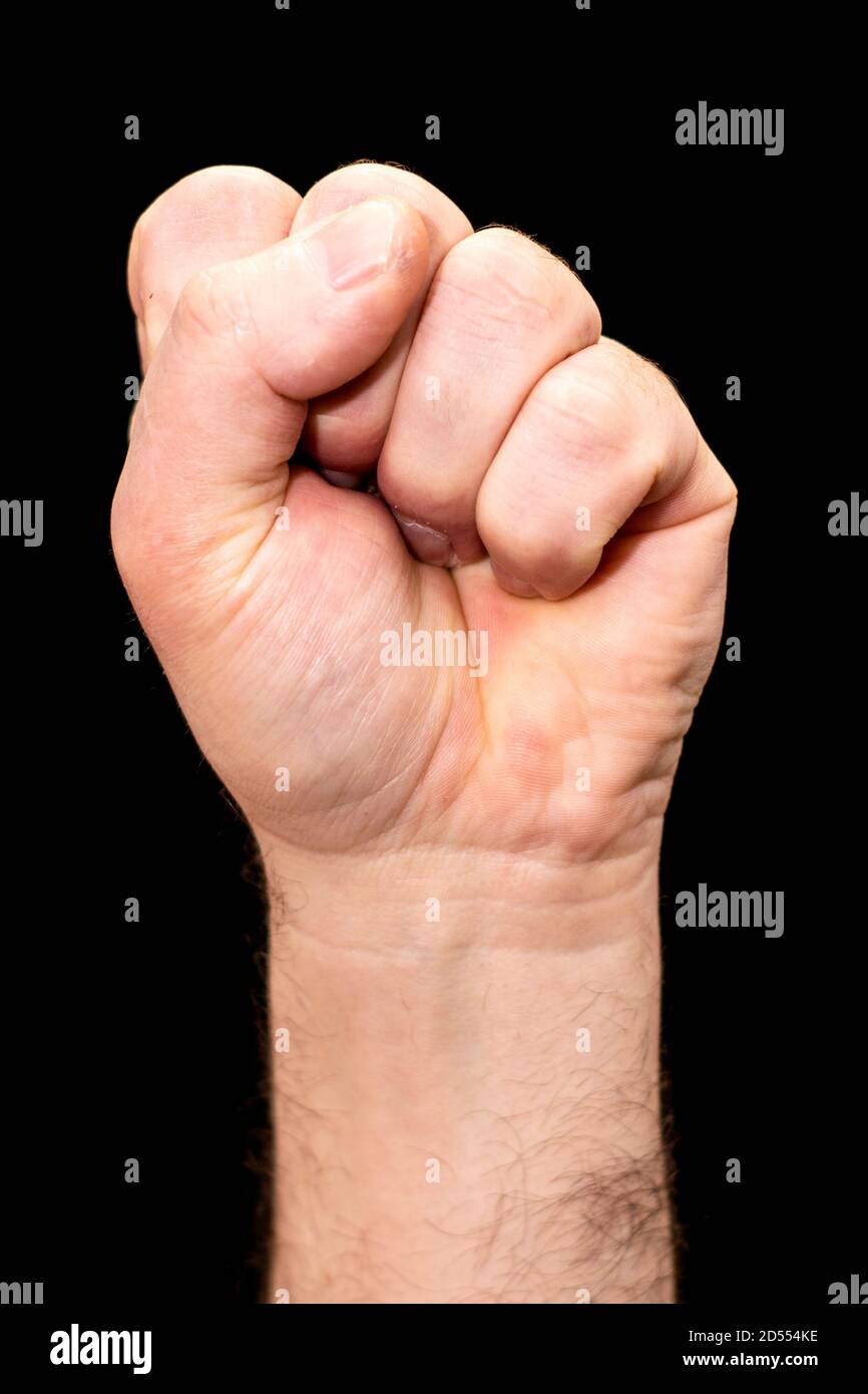 male hand clenched into a fist on a black background Stock Photo - Alamy