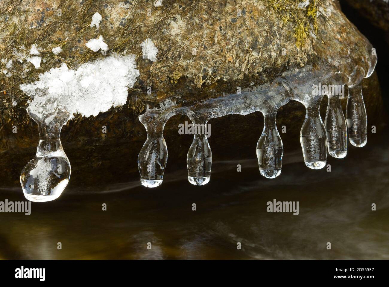 Icecles hanging from a rock over a river Stock Photo - Alamy