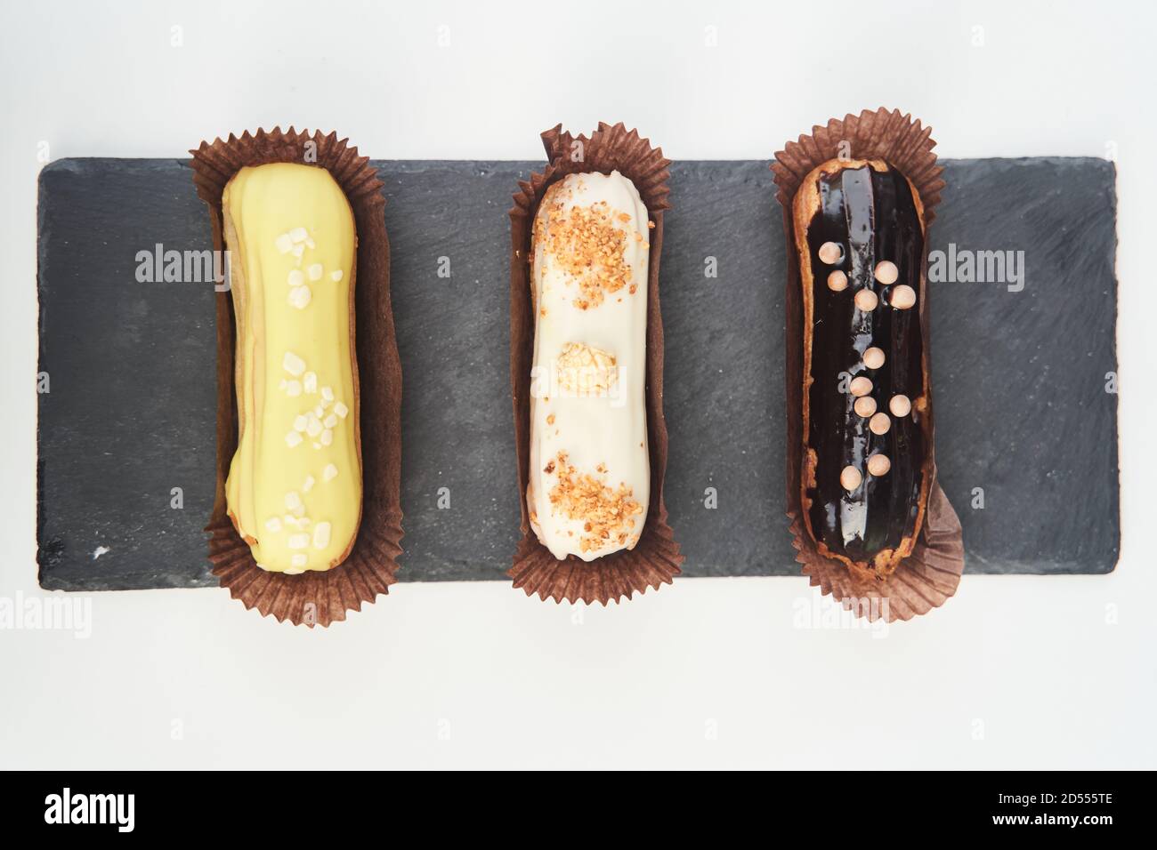 Three eclairs on a black tray top view Stock Photo - Alamy