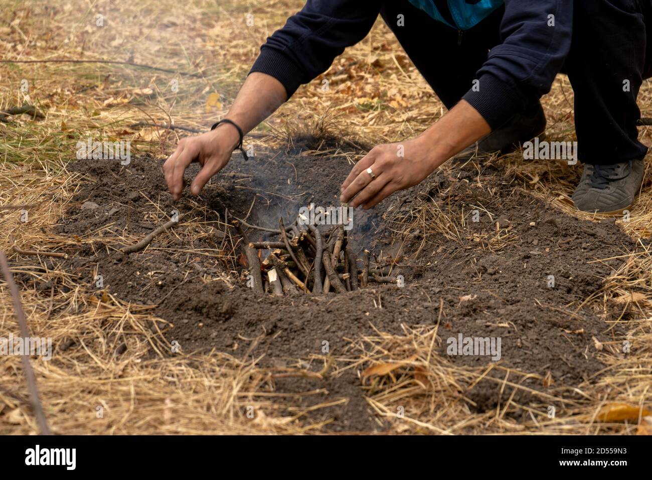Man putting wooden sticks into fire. Bonfire in the forest. Campfire in ...