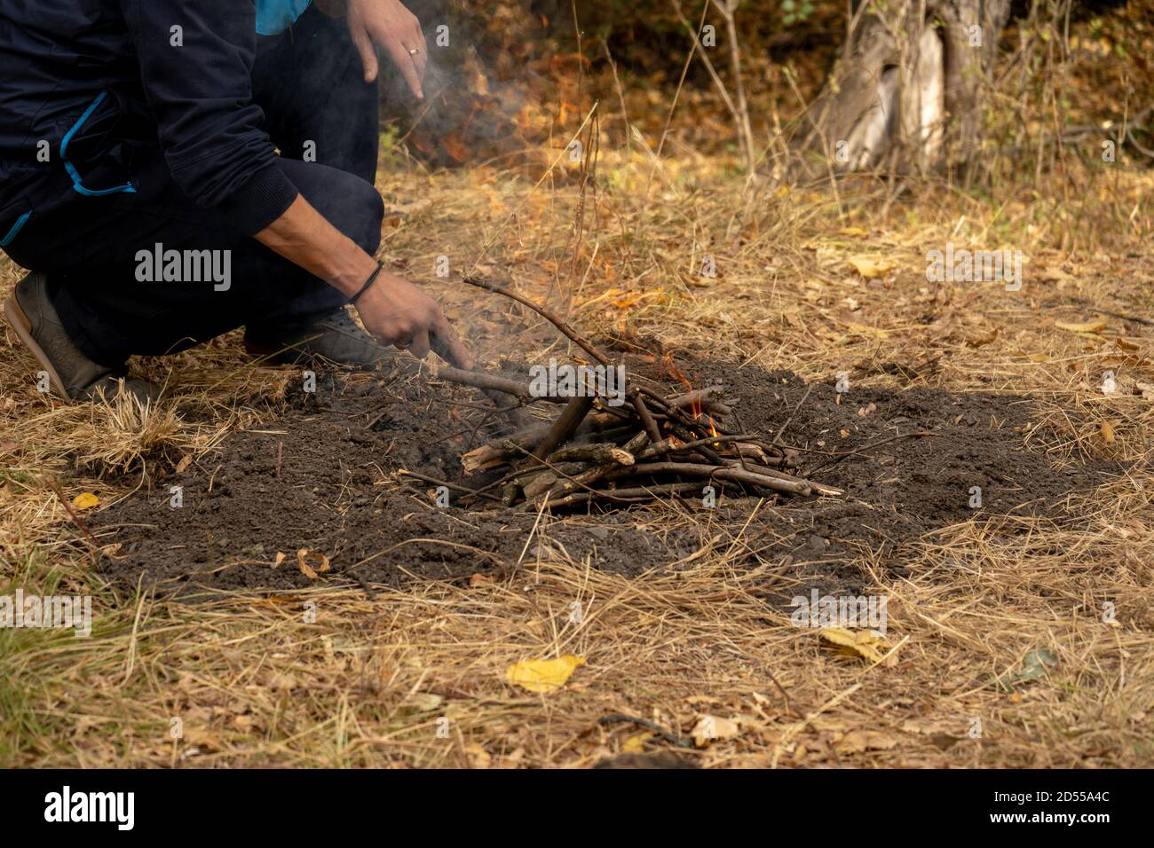 Man putting wooden sticks into fire. Bonfire in the forest. Campfire in ...
