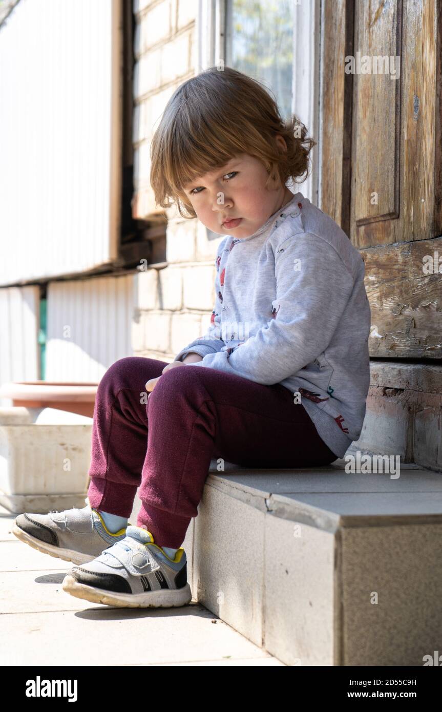 Little three years old boy sitting on stairs. Cute boy with long curly ...