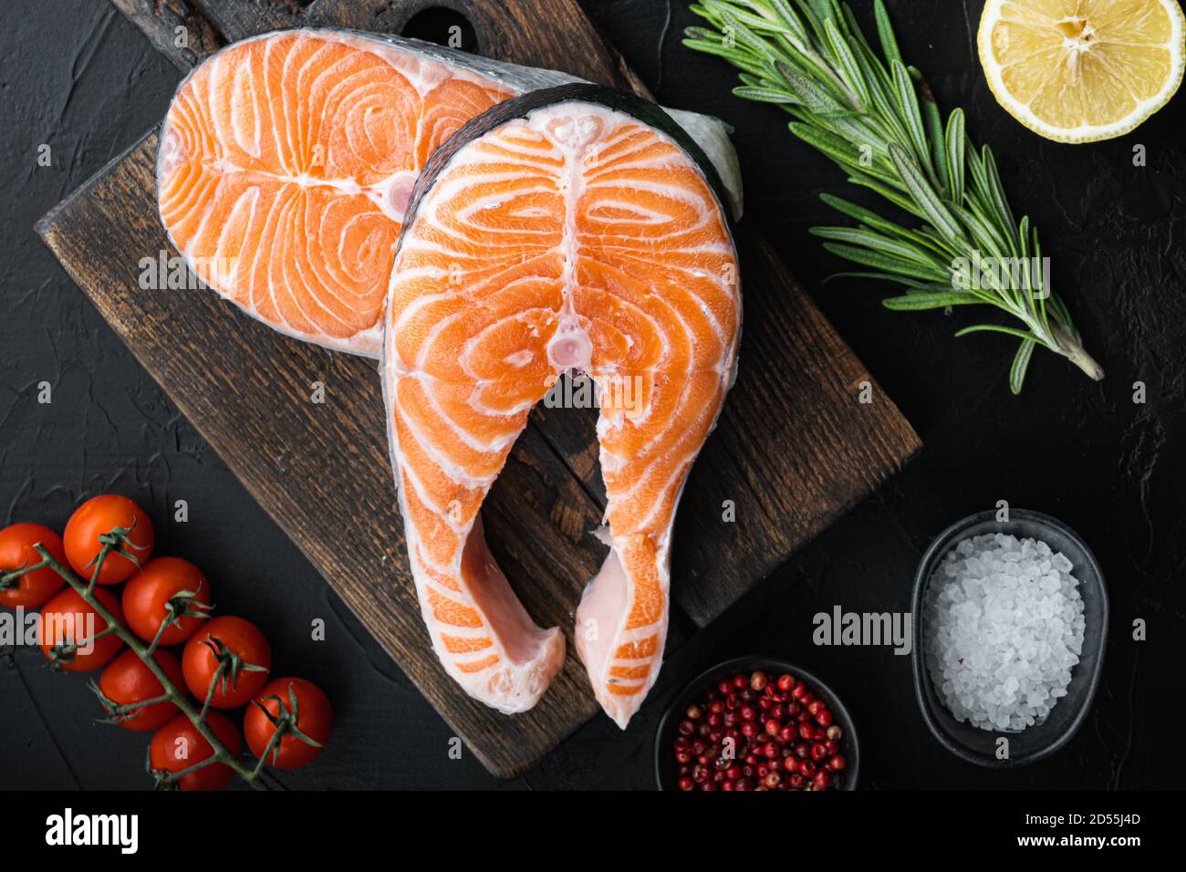 Raw salmon steak with herbs, over black background, flat view Stock ...
