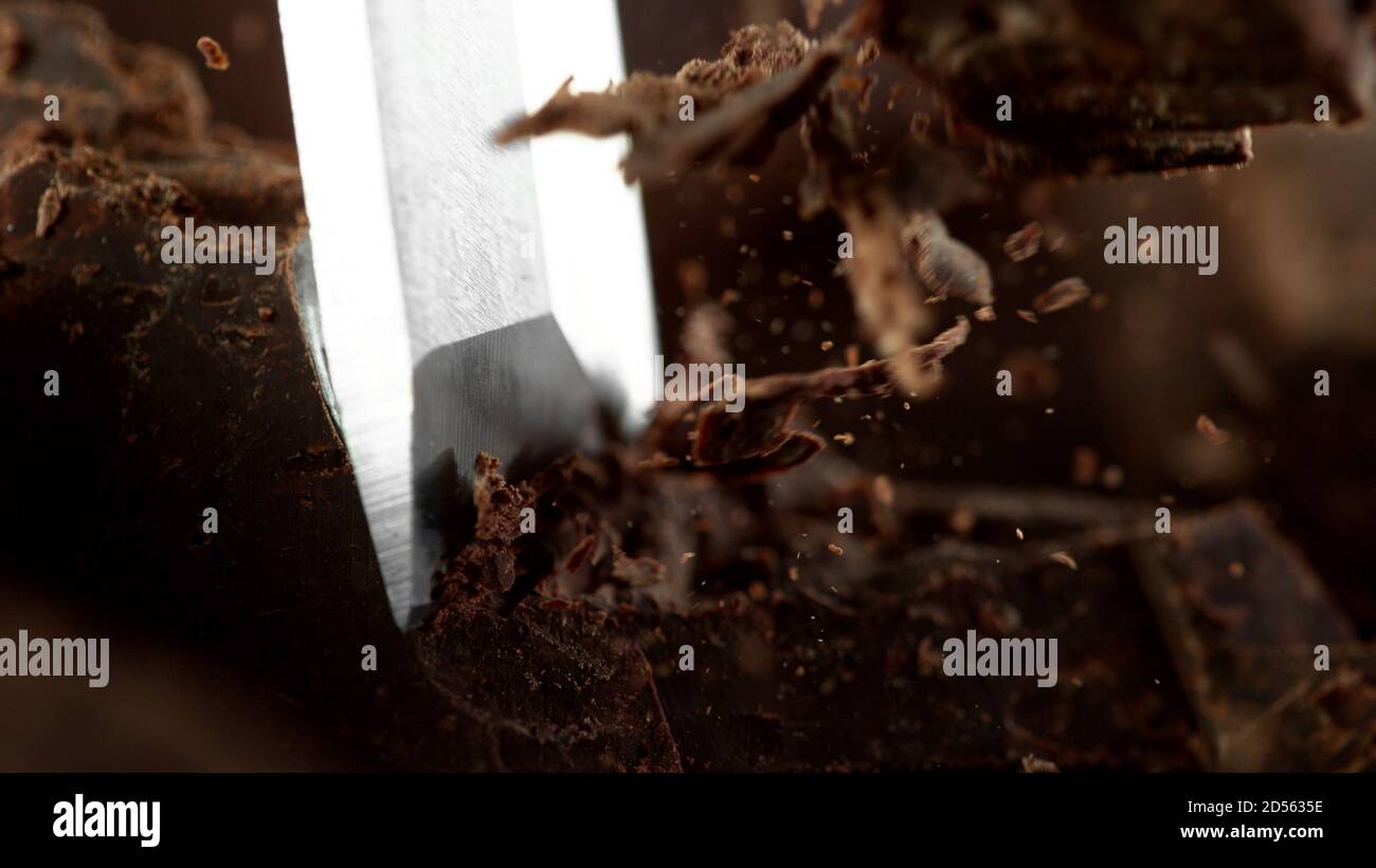 Detail of chisel cutting off raw chocolate, freeze motion of flying ...