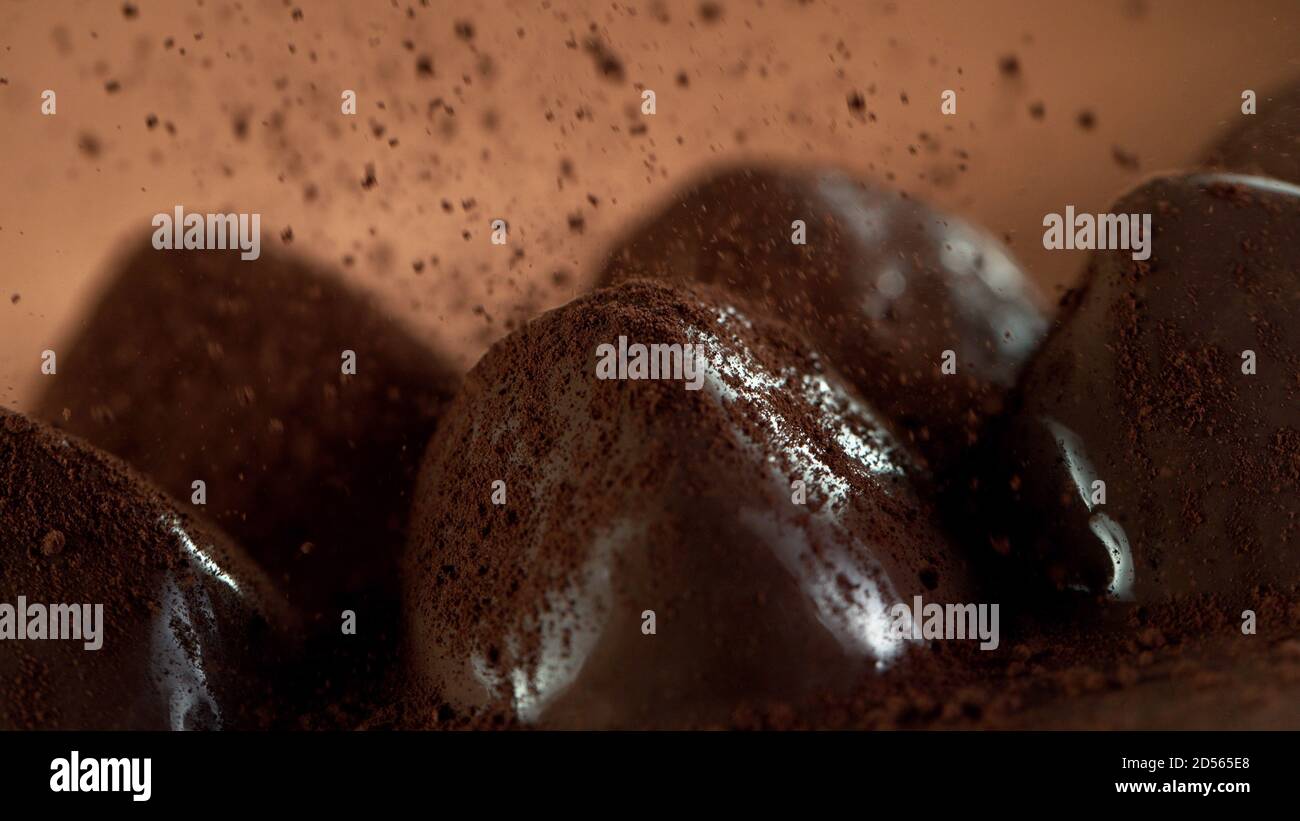 Detail of pralines with falling cocoa powder on top. Studio macro shot ...