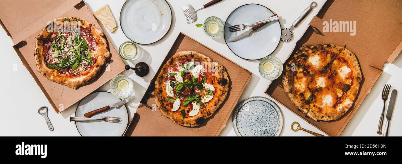 Flat-lay of pizzas in boxes, lemon drinks and cutlery Stock Photo - Alamy
