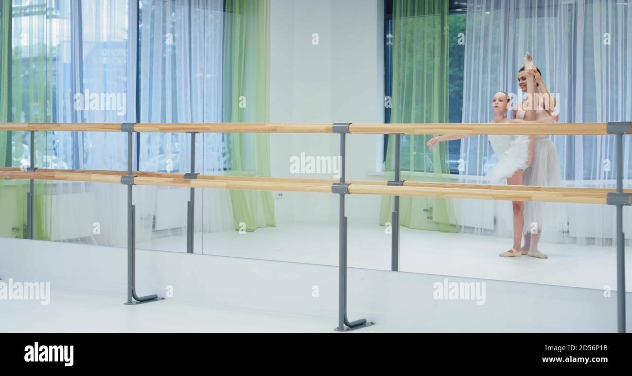Reflection in mirror of girl ballerina raising leg in splits with young ...