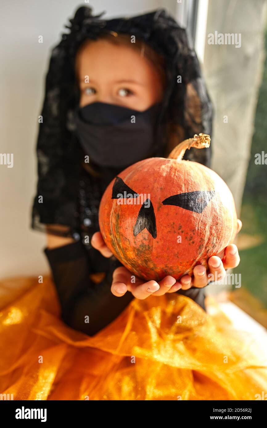 Girl in mask sitting at the windows at home in halloween costume with ...