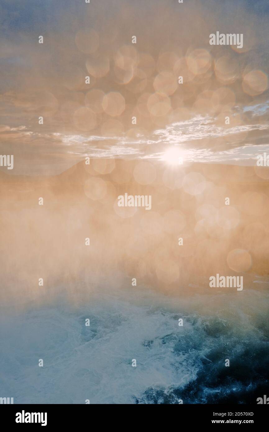 Water droplets above a fast flowing river backlit by a setting sun in ...
