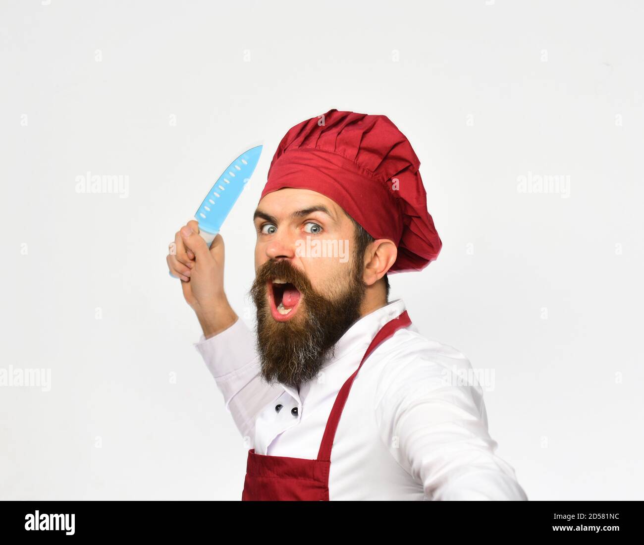 Cook with wild face in burgundy apron and chef hat. Chef pretends to ...