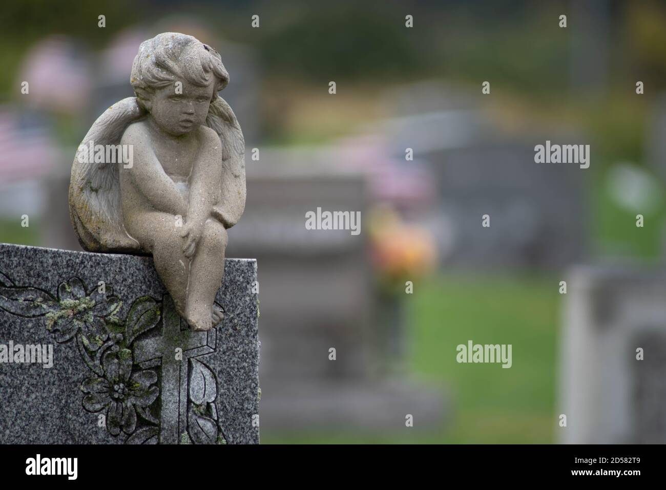 Sad stone angel sits atop a cemetery tombstone Stock Photo - Alamy
