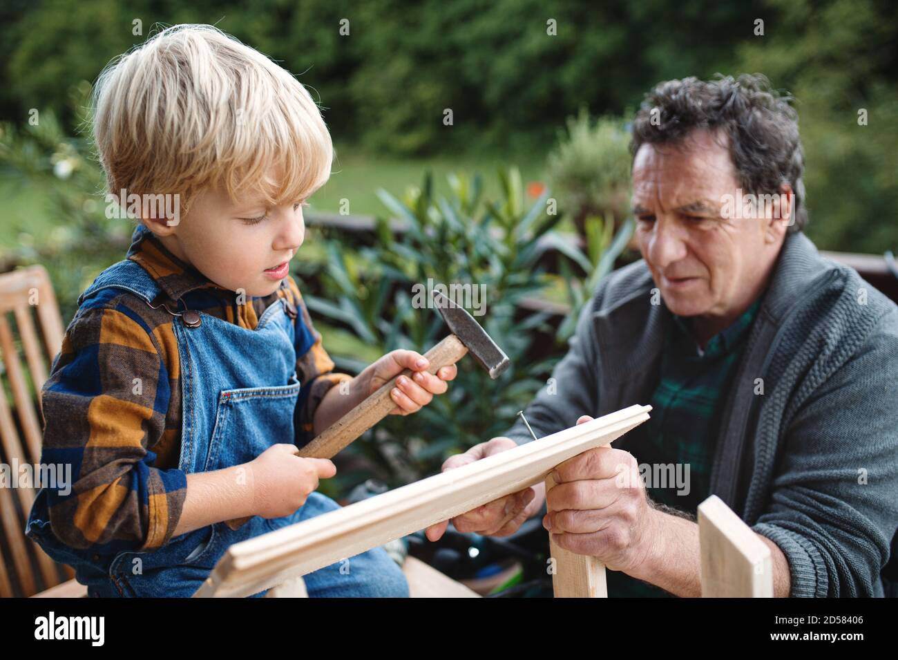 Small boy with senior grandfather constructing birdhouse, diy project ...
